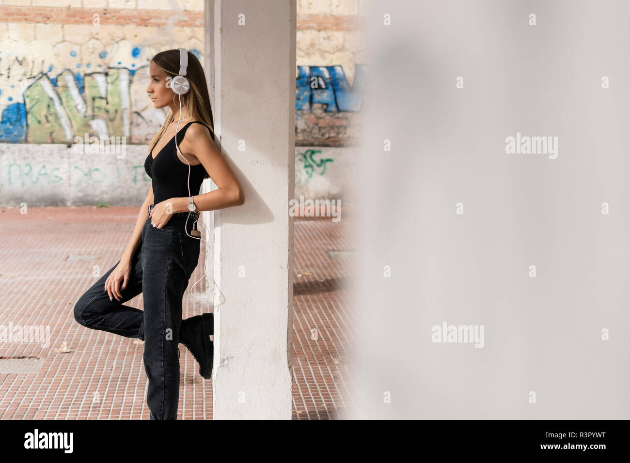 Teenage girl leaning at a column wearing headphones Stock Photo - Alamy