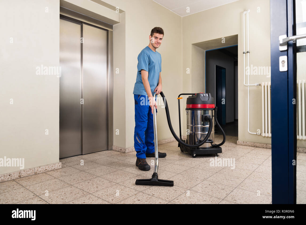 Male Worker Cleaning With Vacuum Cleaner Stock Photo - Alamy