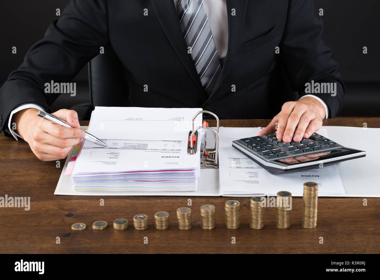 Businessman Calculating Invoice With Coins At Desk Stock Photo - Alamy