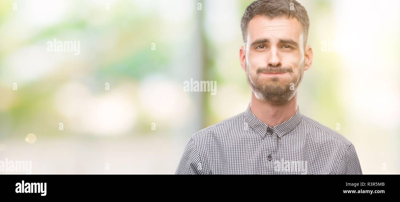 Young hipster man puffing cheeks with funny face. Mouth inflated with ...