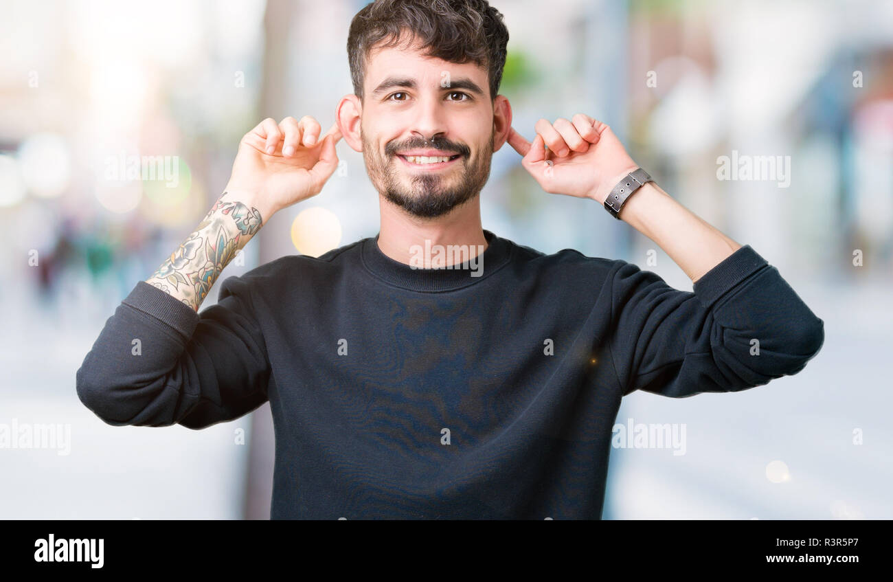 Young handsome man over isolated background Smiling pulling ears with ...