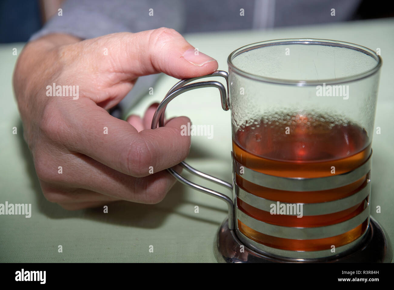 Hand holding a hot glass of tea Stock Photo - Alamy