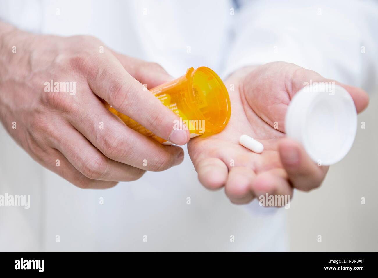 Pharmacist pouring pill into hand Stock Photo - Alamy