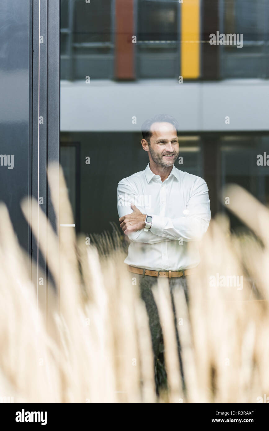 Portrait of smiling businessman looking out of window Stock Photo - Alamy