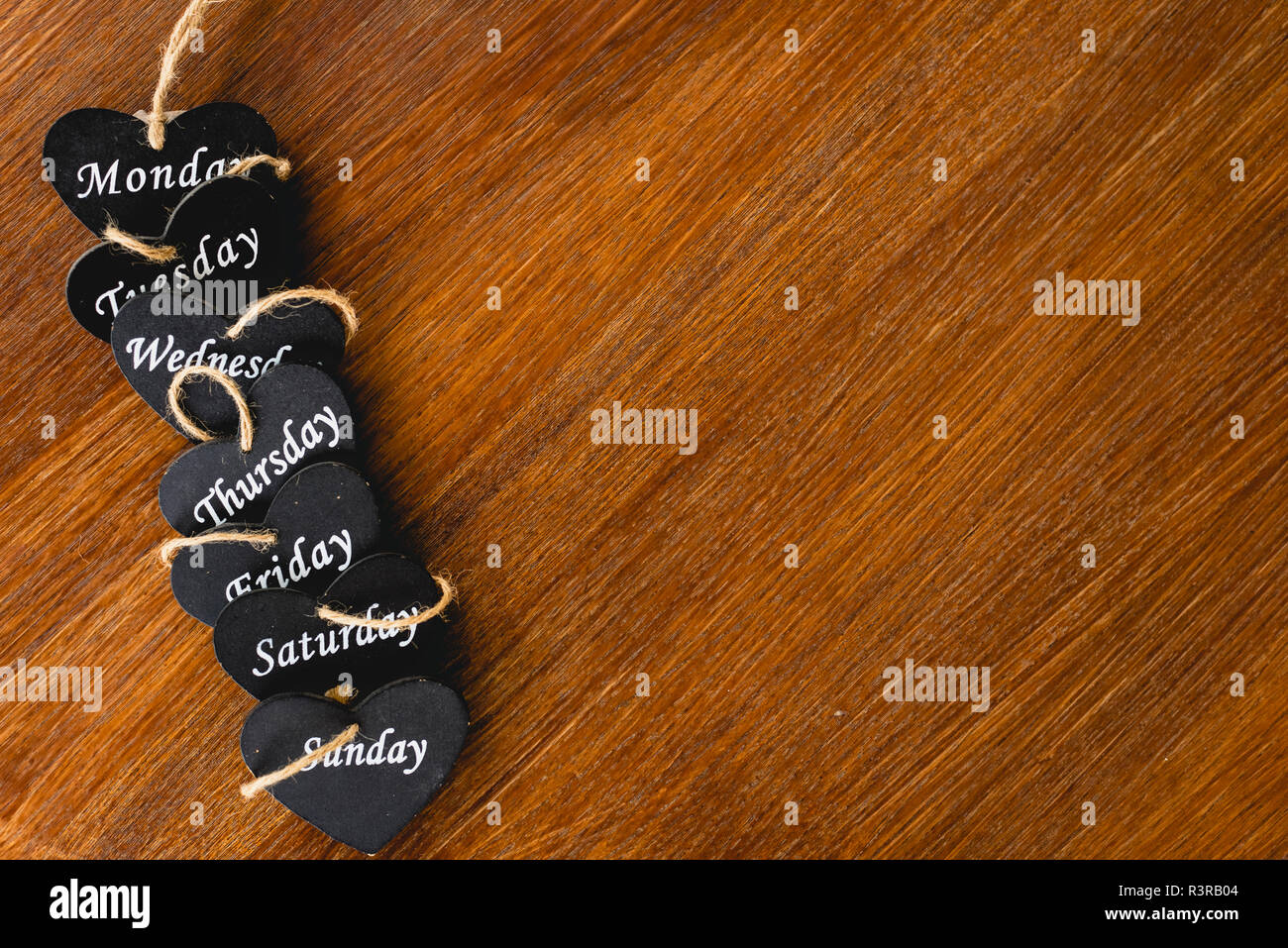 Heart of black wood with days of the week written on it Stock Photo - Alamy