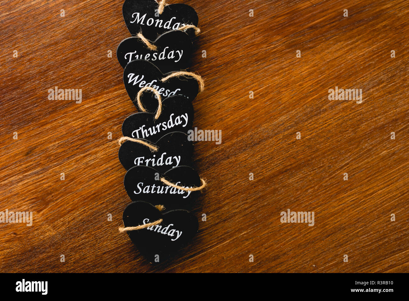 Heart of black wood with days of the week written on it Stock Photo - Alamy