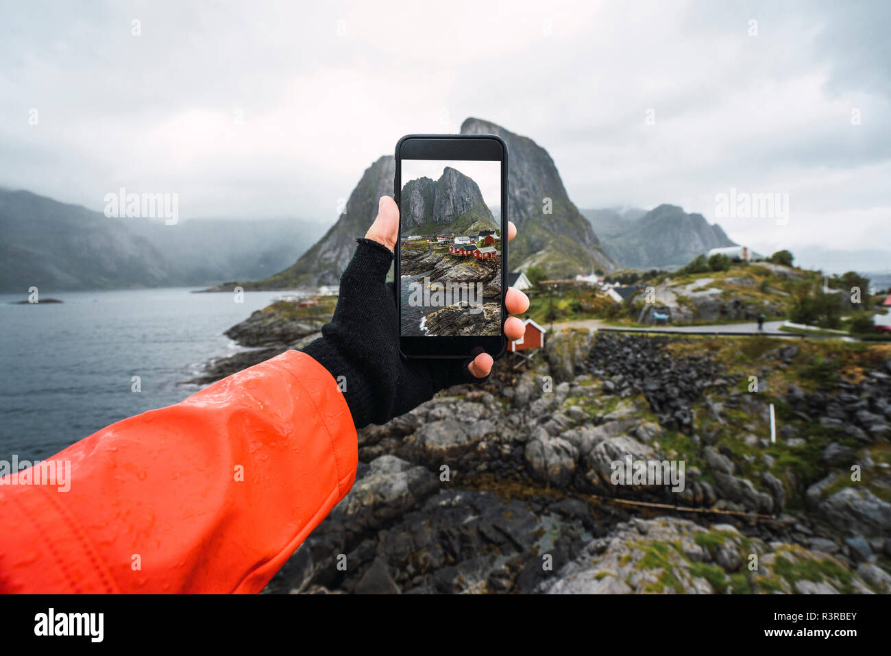 Norway, Lofoten, man's hand taking cell phone picture at the coast ...