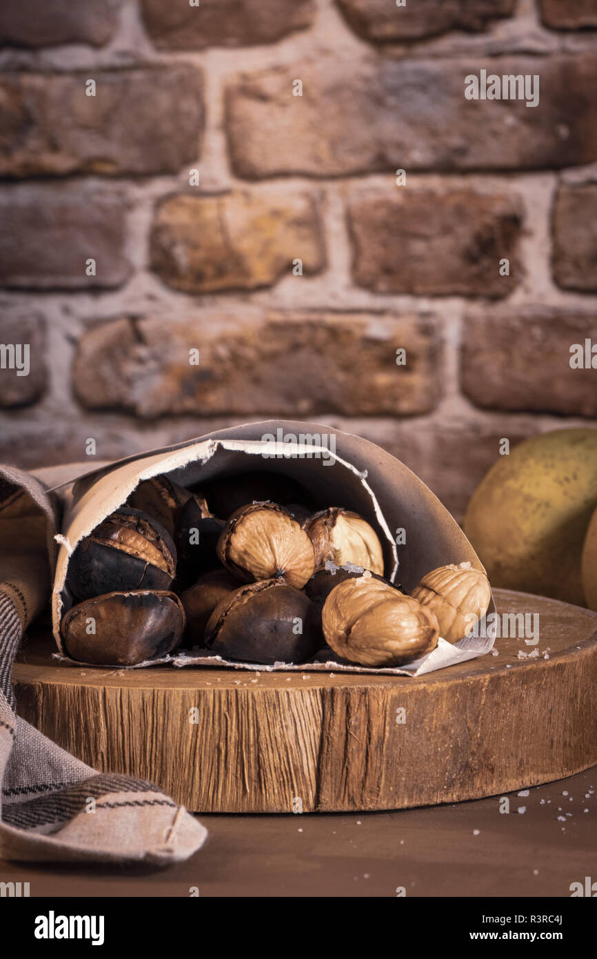 Roasted chestnuts in a paper cone, on a rustic kitchen countertop Stock ...
