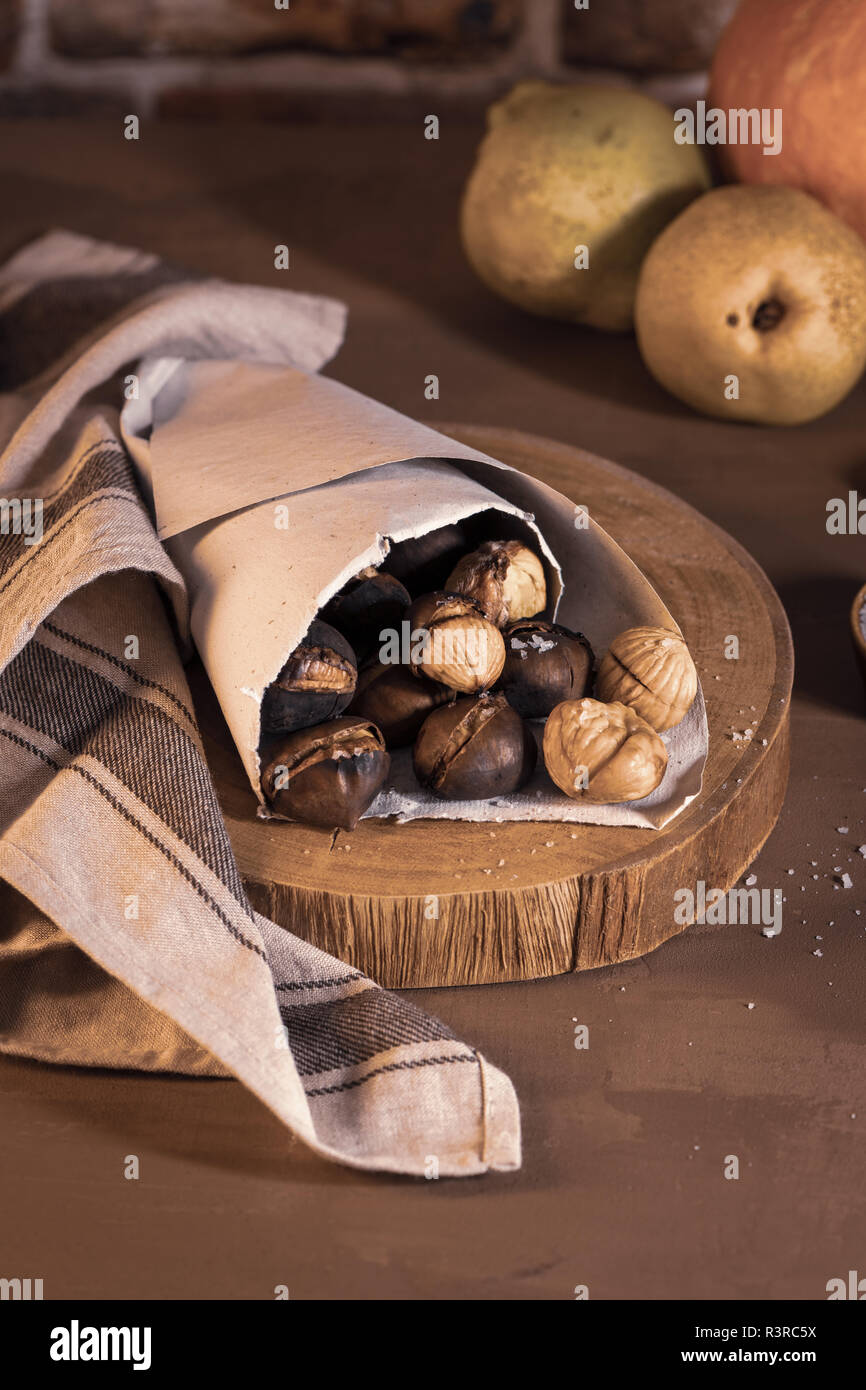 Roasted chestnuts in a paper cone, on a rustic kitchen countertop Stock ...