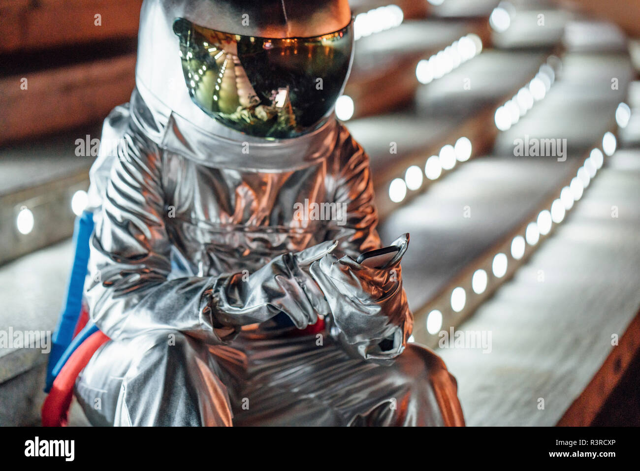Spaceman sitting on illuminated stairs at night using cell phone Stock ...