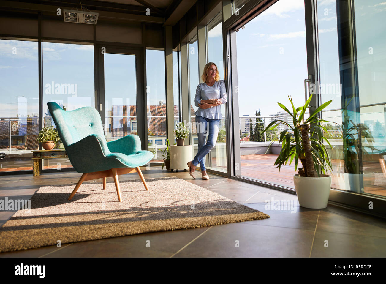 Mature woman standing at the window at home looking out Stock Photo - Alamy