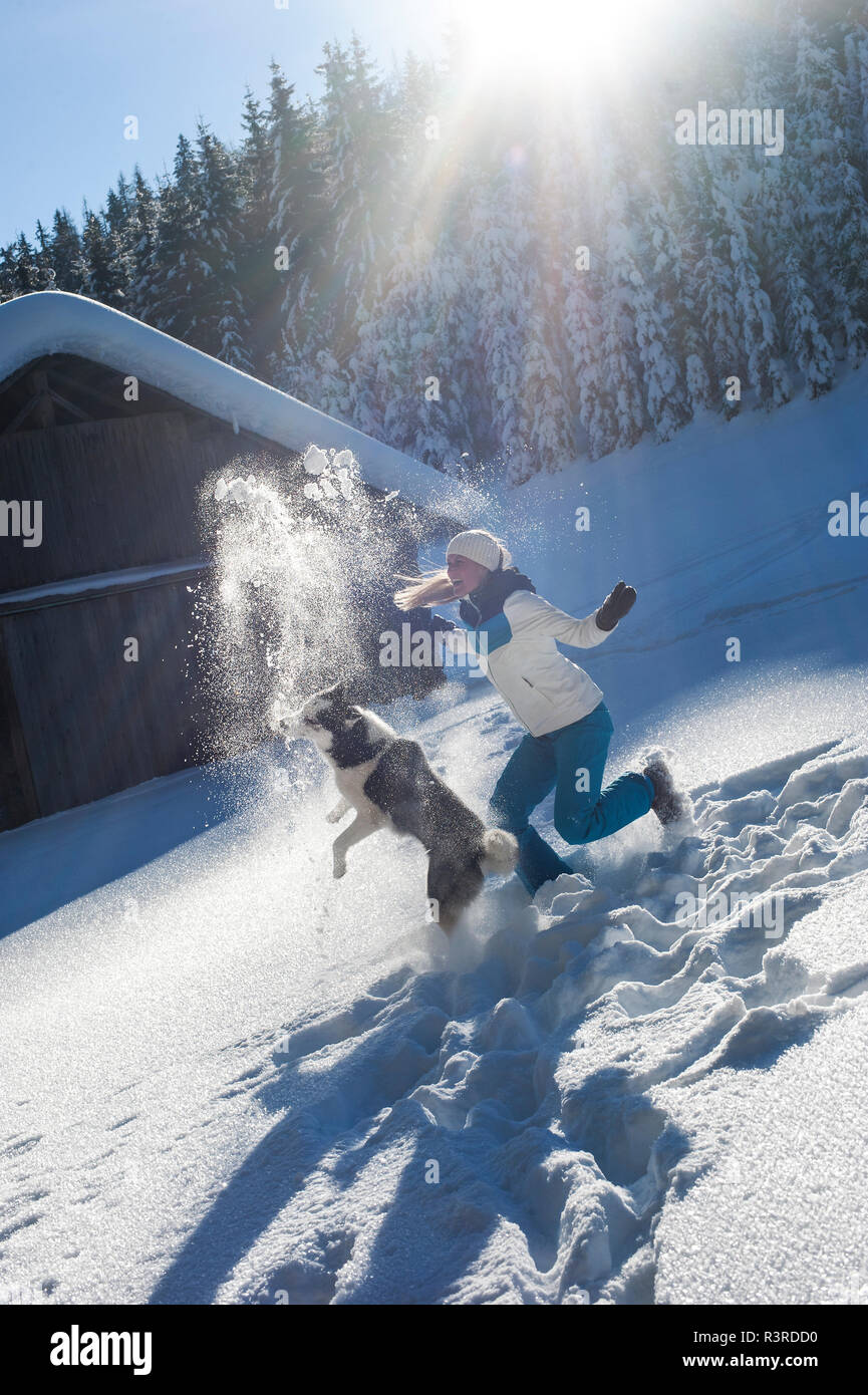 Austria, Altenmarkt-Zauchensee, happy young woman playing with dog in ...