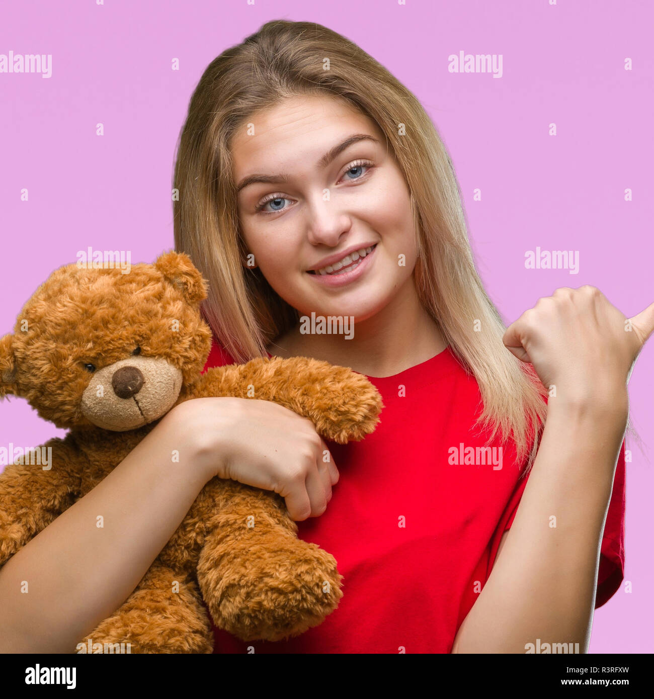 Young caucasian woman holding cute teddy bear over isolated background ...
