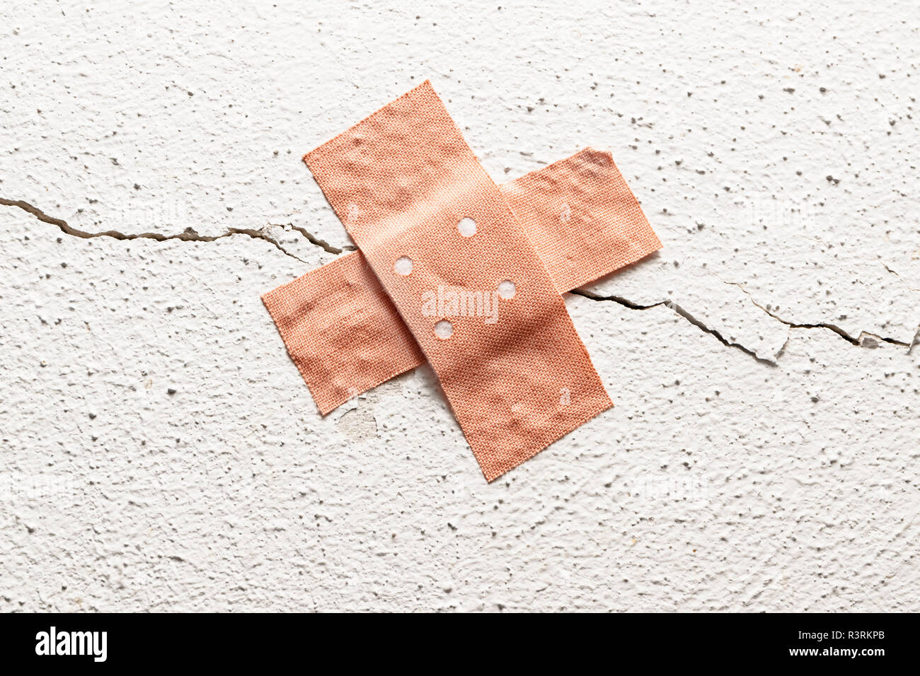 band-aid plaster in cross shape on a crack in the wall, concept for ...