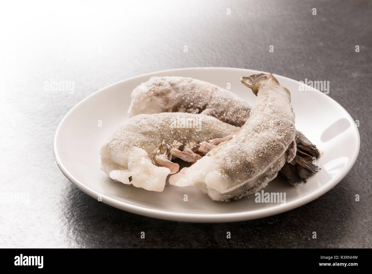 frozen king prawns without head on a plate, copy space, selected focus ...