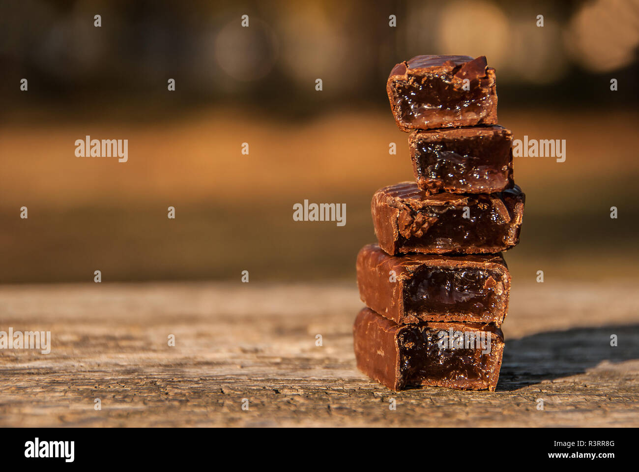 Five chocolate candies filled with marmalade on wooden bench in park ...