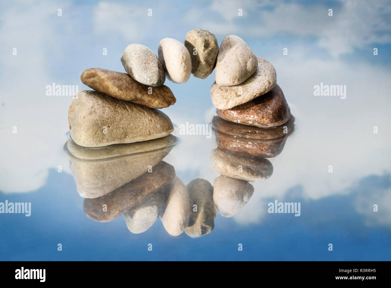 arch, bridge or gate made of balanced pebbles with reflection in the ...