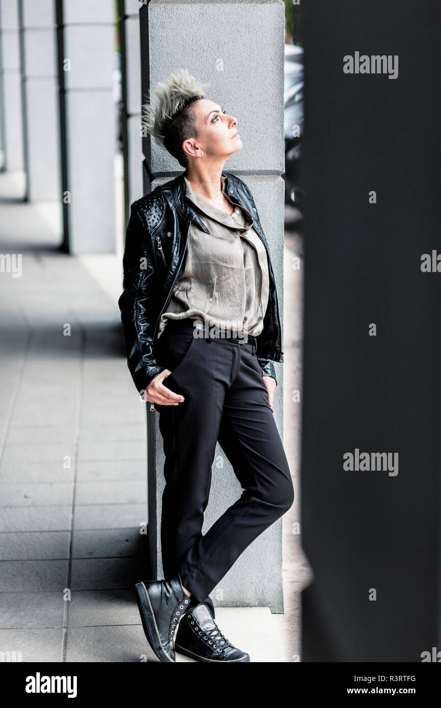 Punk woman leaning against a column looking up Stock Photo - Alamy