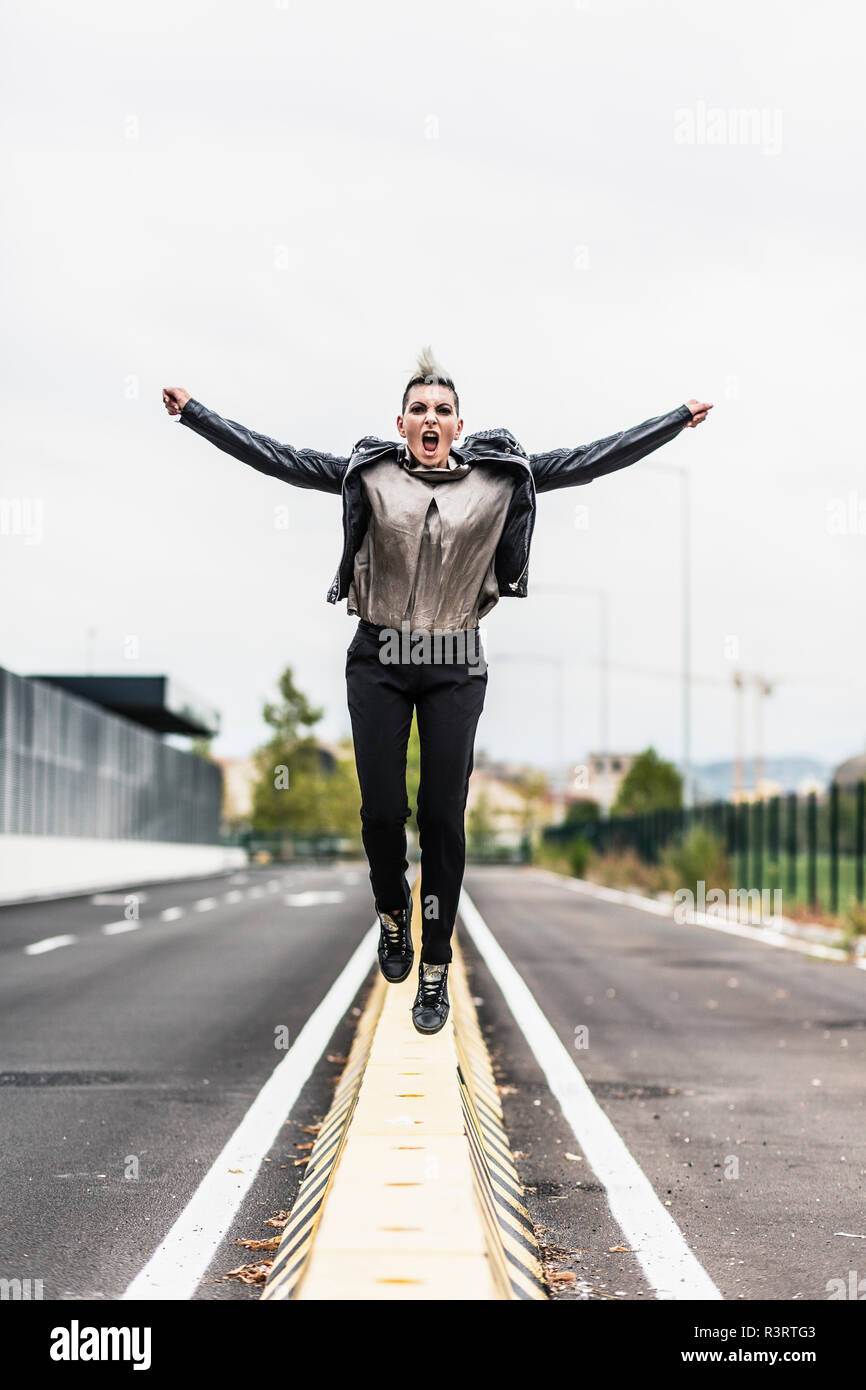 Punk woman screaming and jumping on a barrier at the roadside Stock ...
