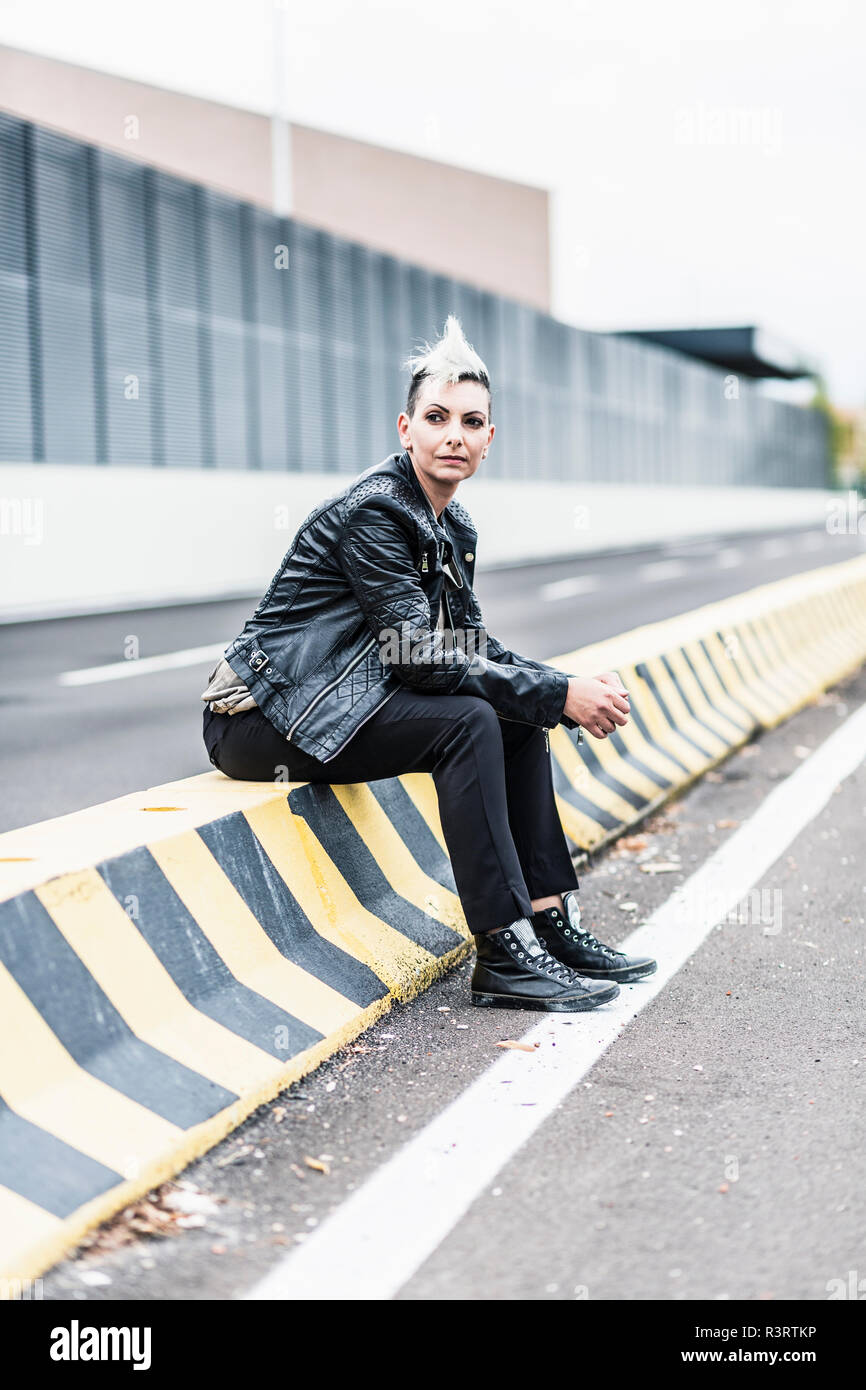 Punk woman sitting at the roadside looking around Stock Photo - Alamy