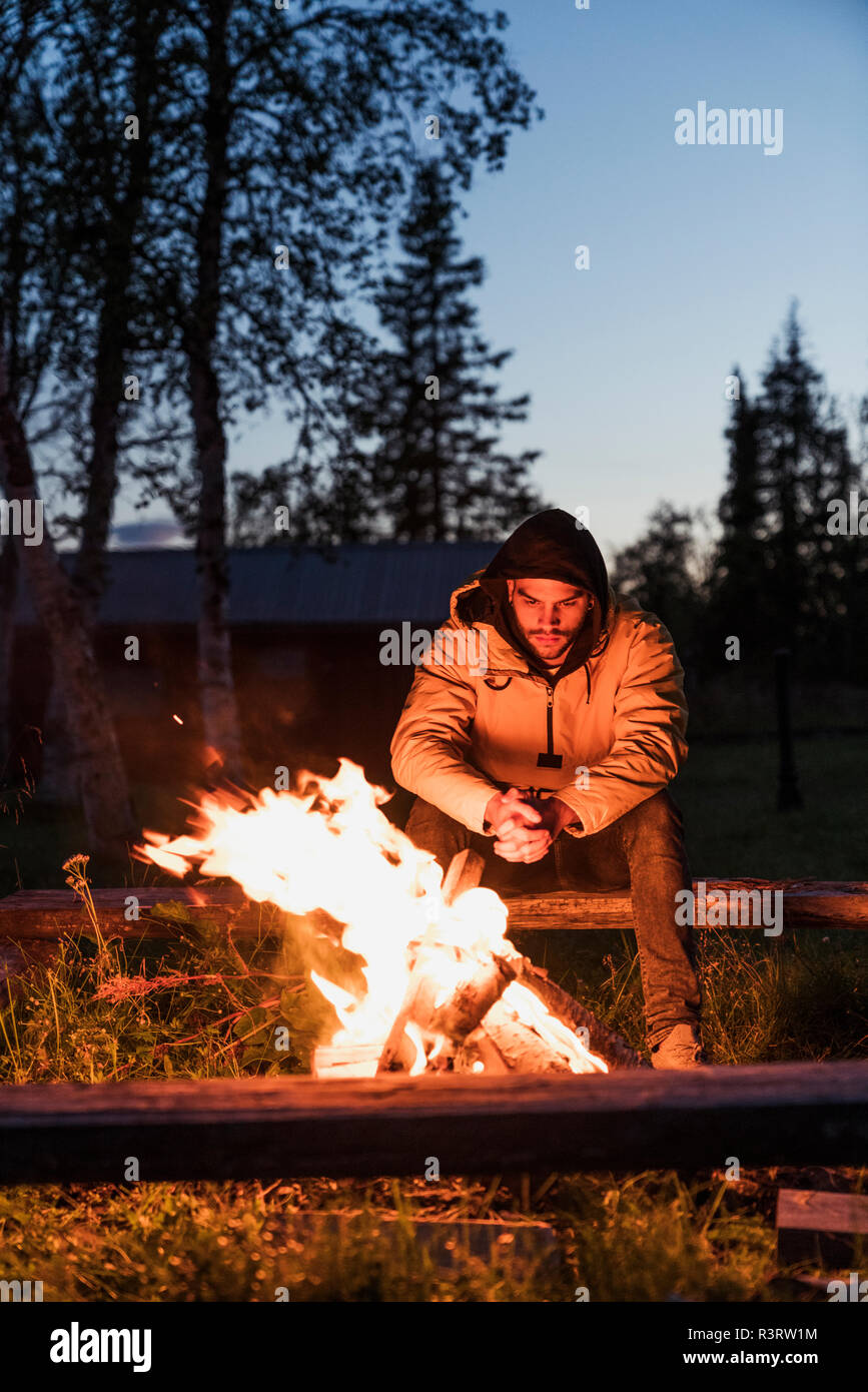 Young man sitting campfire hi-res stock photography and images - Alamy