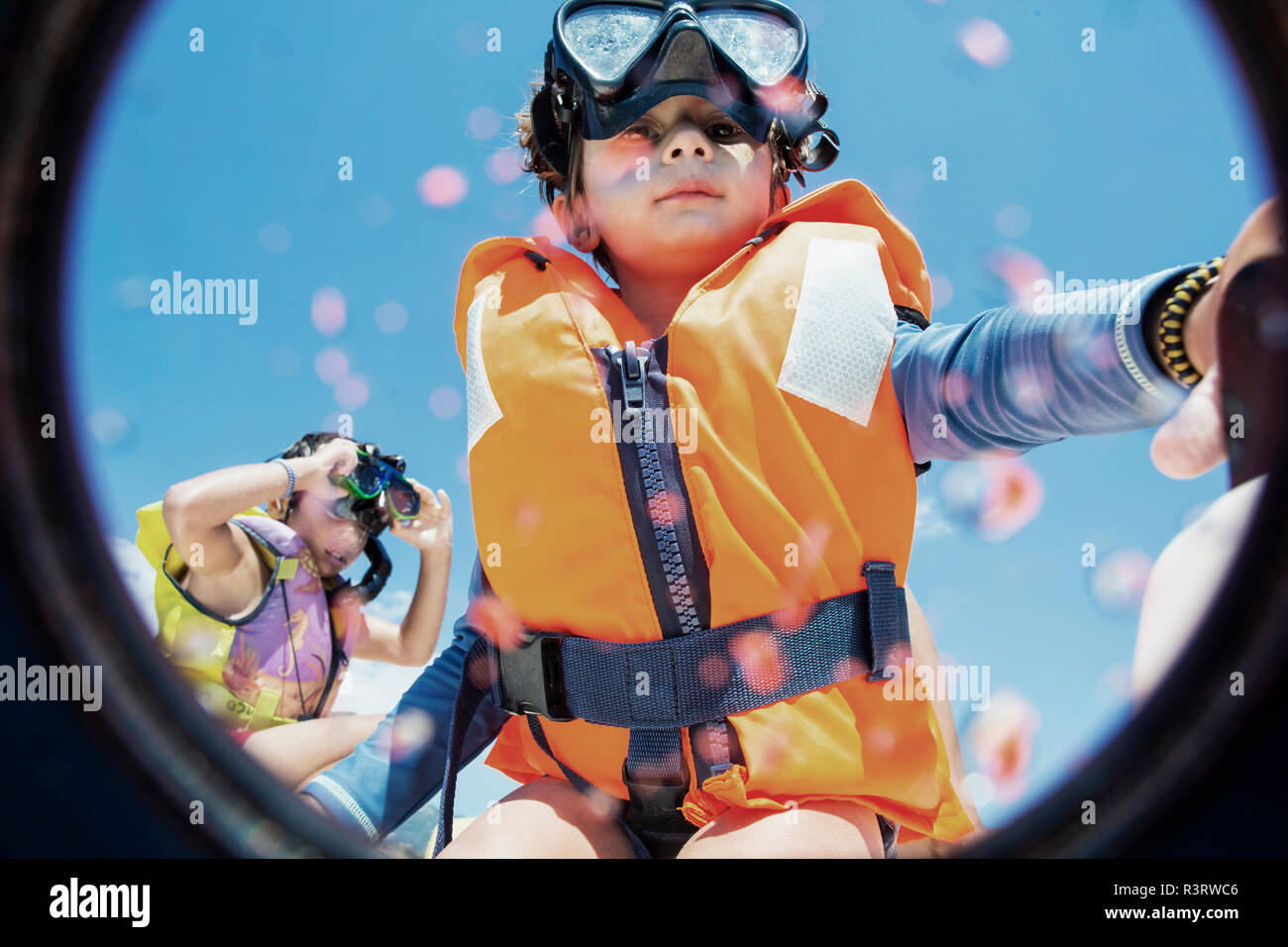 Toddler wearing life jacket and diving goggles with brother in ...