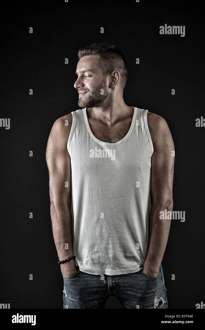 Macho in vest with muscular hands in jeans pockets. Man with smile on ...