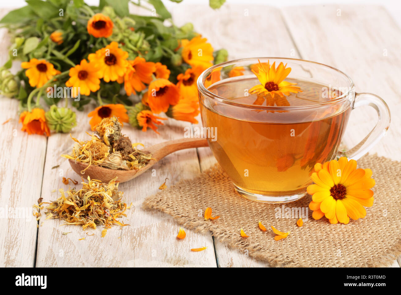 Calendula tea with fresh and dried flowers on white wooden background ...