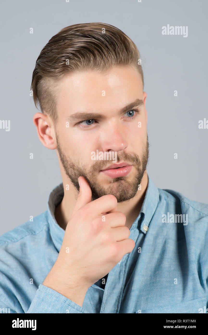 Man touch beard on unshaven face. Macho with stylish hair, haircut on ...