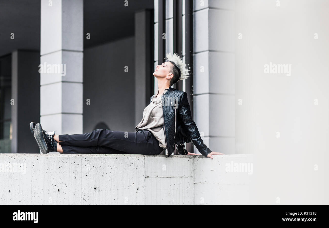 Punk woman sitting on a wall with closed eyes Stock Photo - Alamy