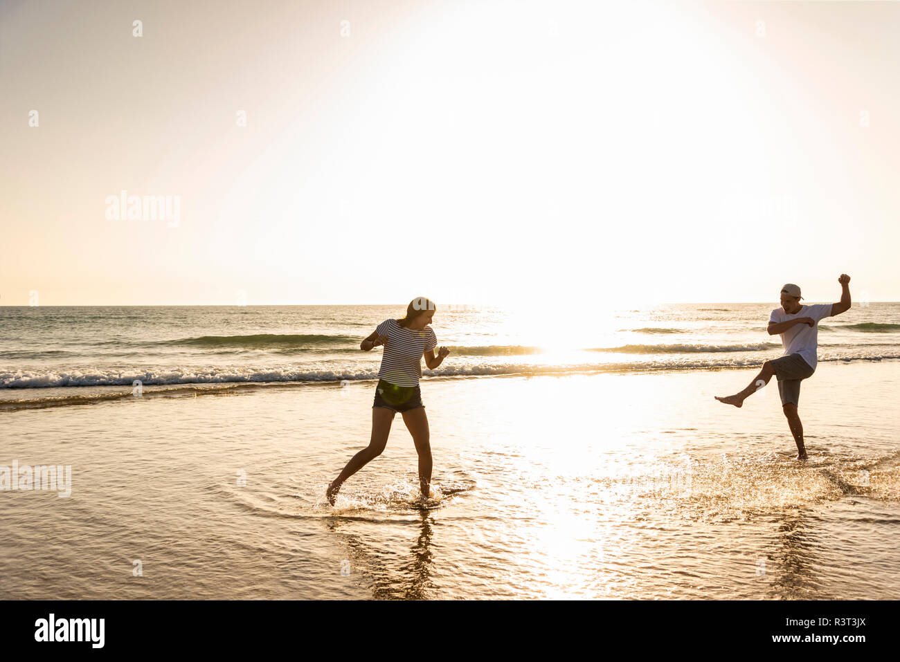 Young couple having fun at the beach, splashing water in the sea Stock ...