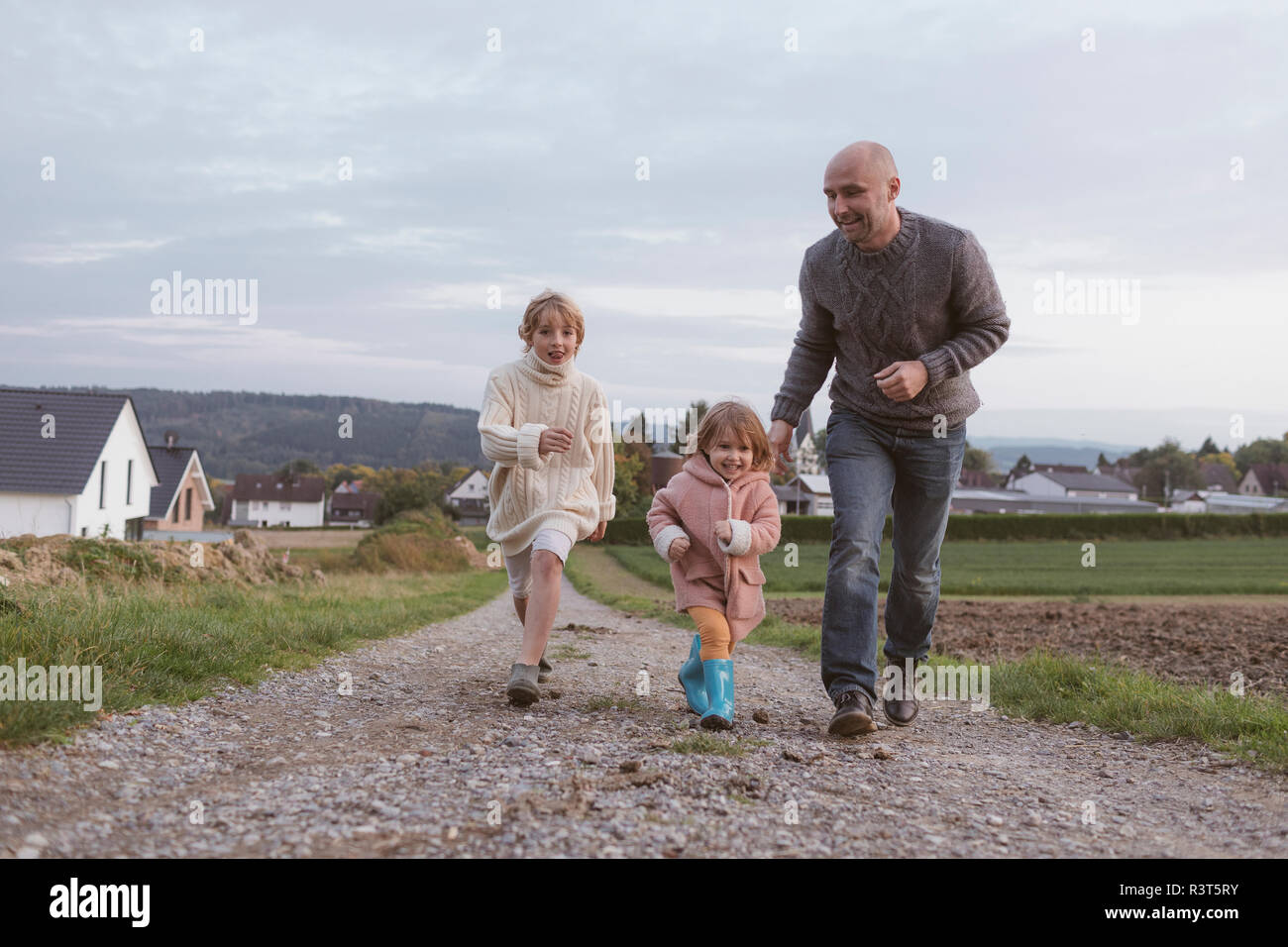Father with two children running on field path Stock Photo - Alamy