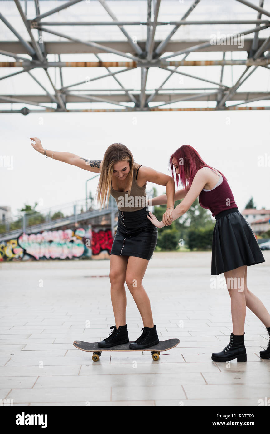 Young woman pushing friend on skateboard in the city Stock Photo - Alamy