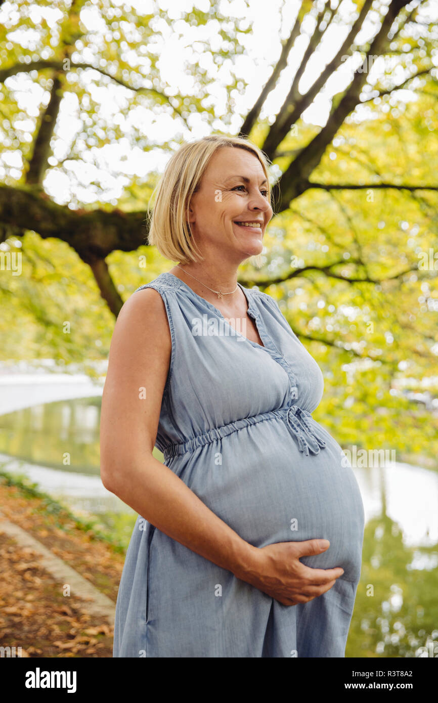 Happy mature pregnant woman standing in park Stock Photo - Alamy