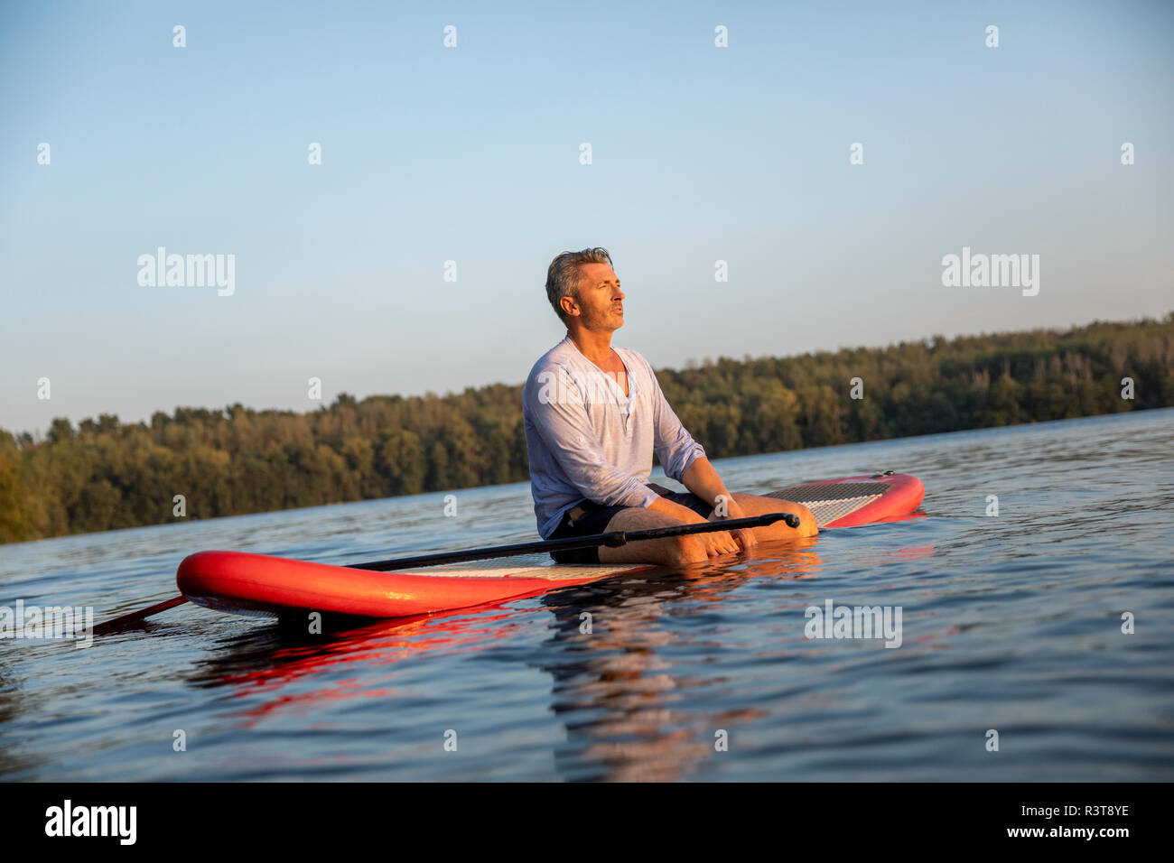 Man sitting paddleboard lake sunset relaxing hi-res stock photography ...