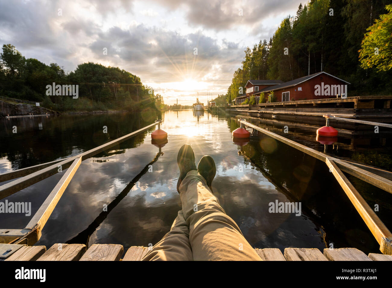 Finland, Kajaani, Man sitting on jetty, watching sunset Stock Photo - Alamy