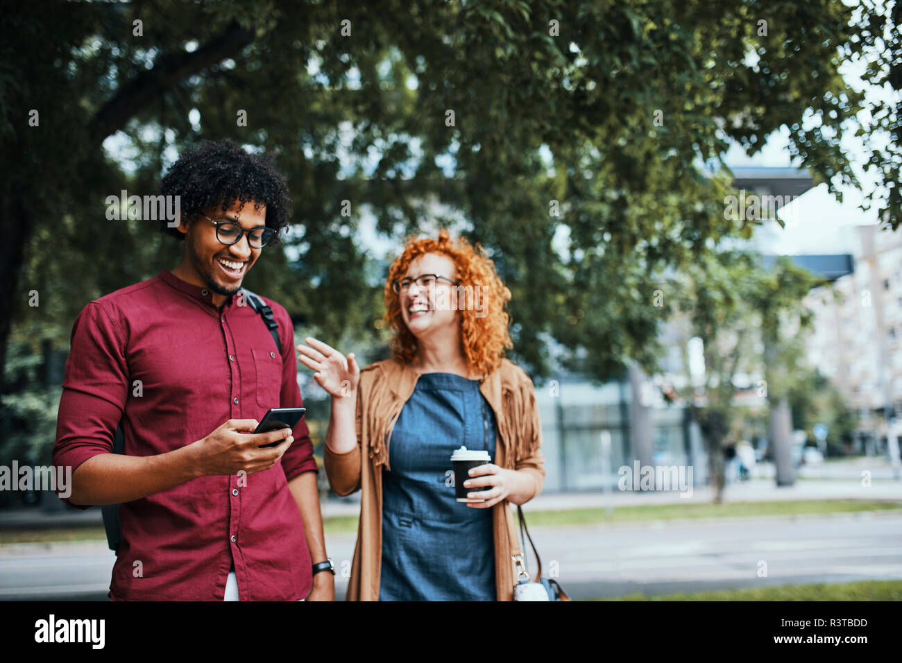 Colleagues walking in the city, talking, using smartphone Stock Photo ...