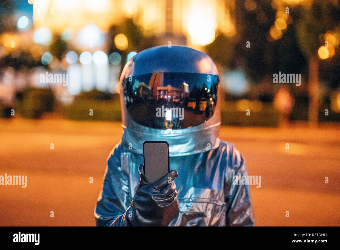Spaceman on a street in the city at night holding smartphone Stock ...