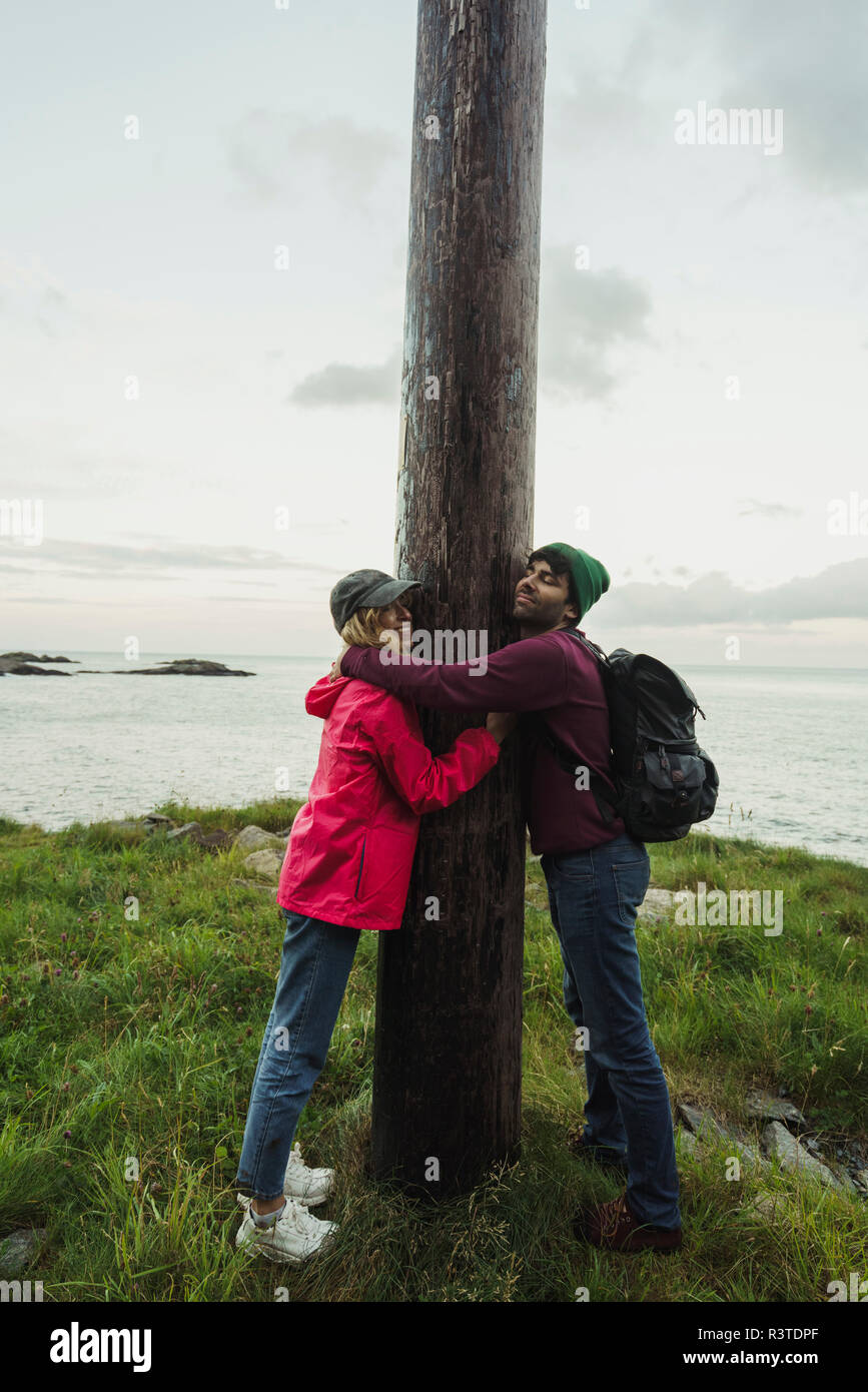 Norway, Lofoten, young couple hugging a pole at the coast Stock Photo ...