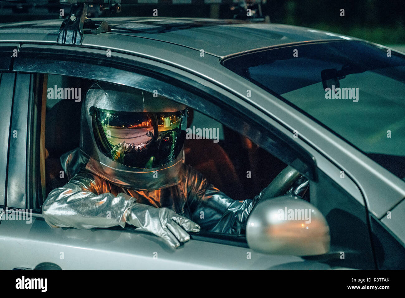 Spaceman sitting in car at night Stock Photo - Alamy