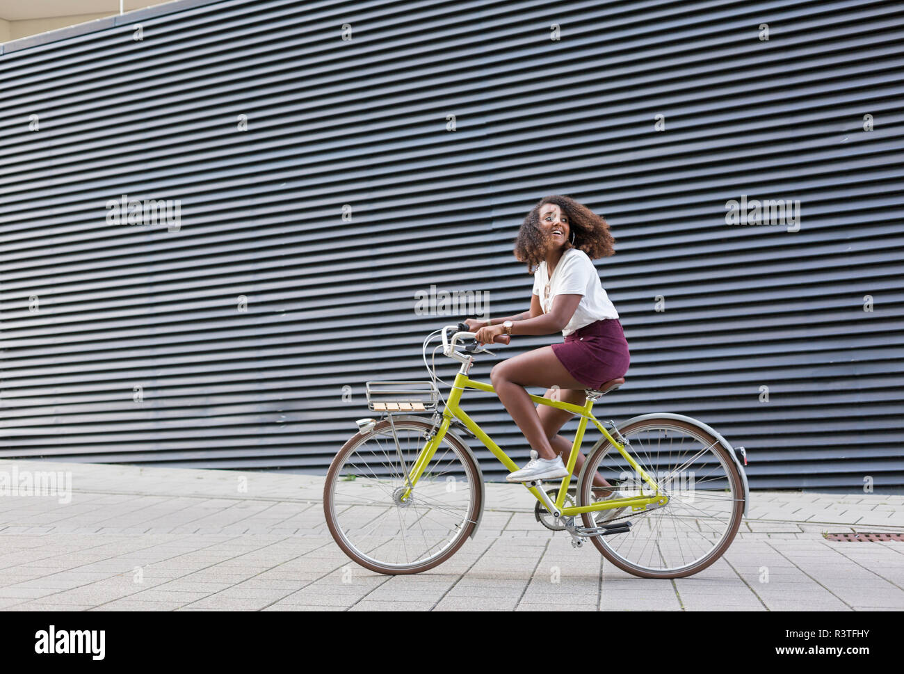 Smiling young woman riding bicycle Stock Photo - Alamy