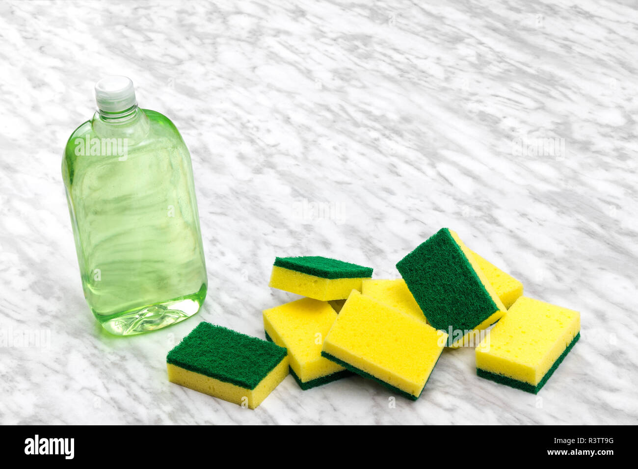 Green and yellow sponges and dishwashing liquid and on marble kitchen ...