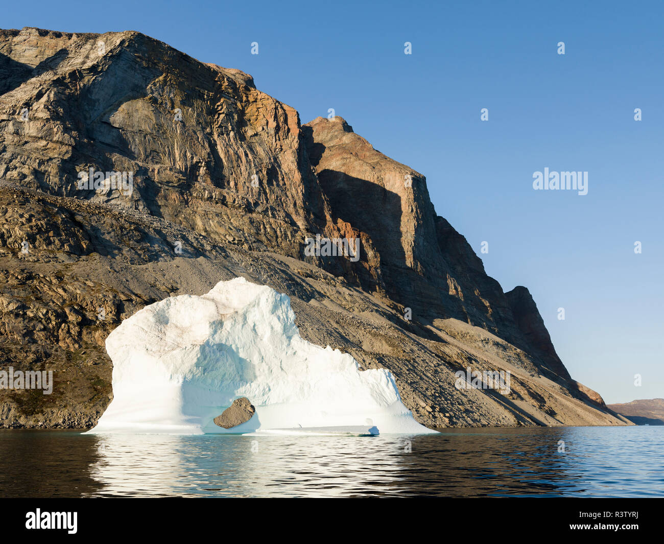 Landscape with steep yellow cliffs and icebergs in the Uummannaq fjord ...