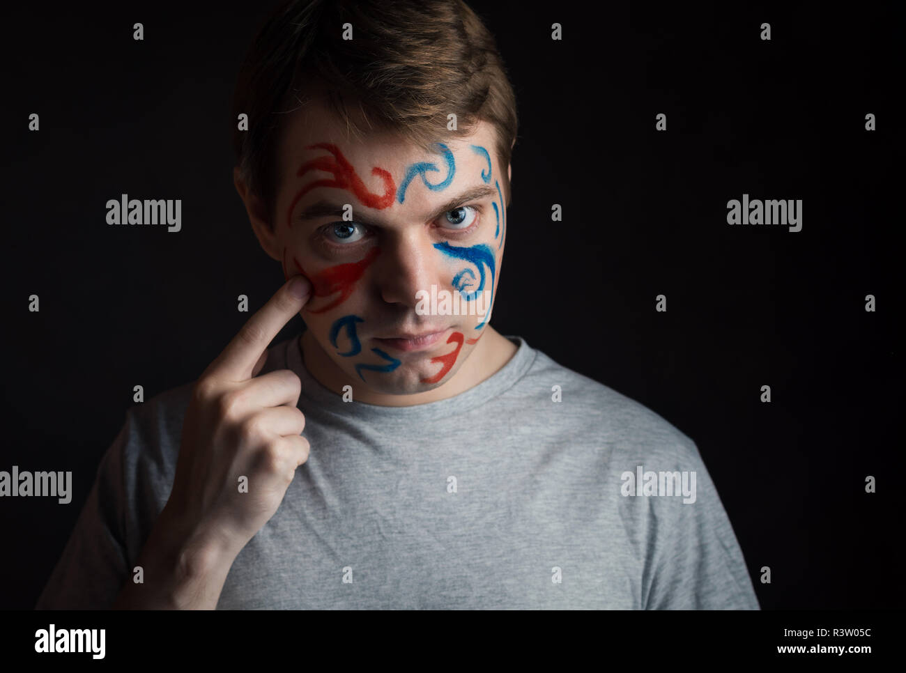 Portrait of young man with paint on his face on dark background Stock ...