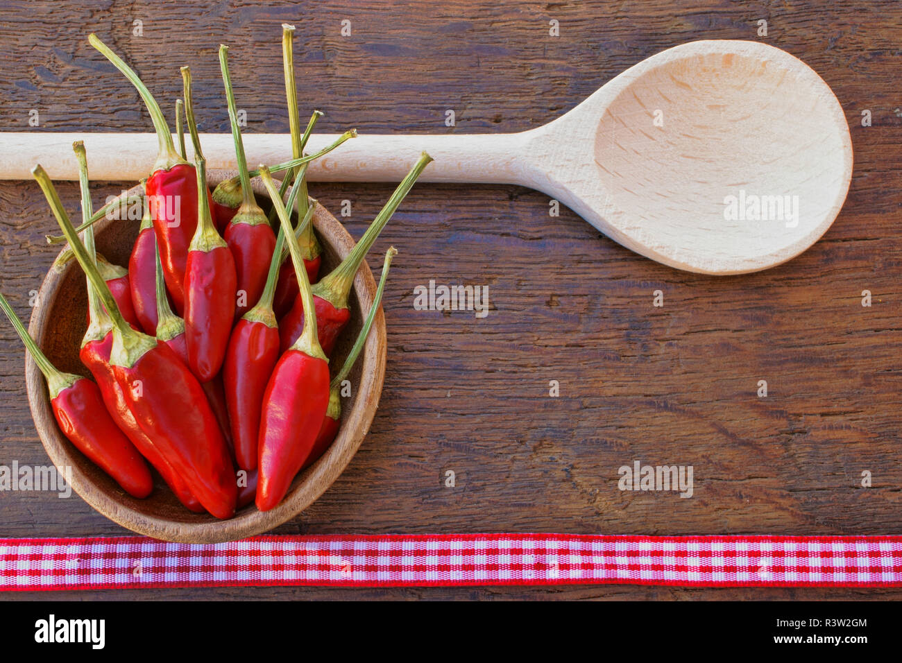 bowl of fresh chili peppers and a wooden cooking spoon Stock Photo - Alamy
