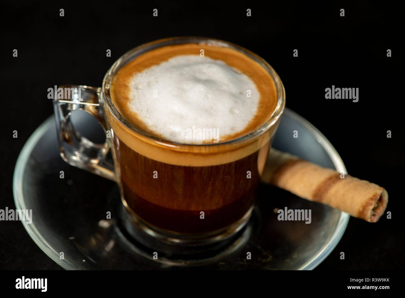 Italian Macchiato coffee with wafer roll with isolated black background ...