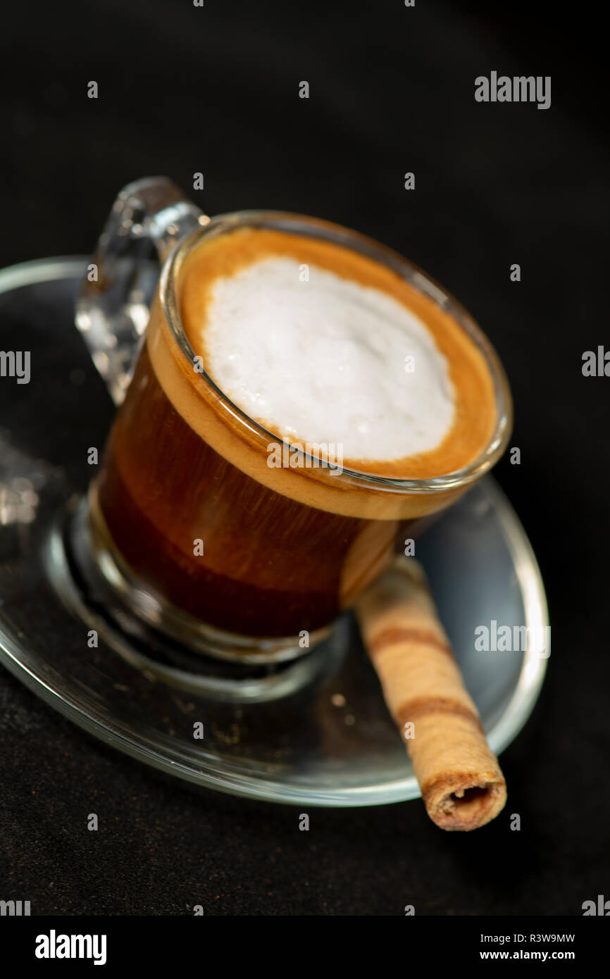 Italian Macchiato coffee with wafer roll with isolated black background ...