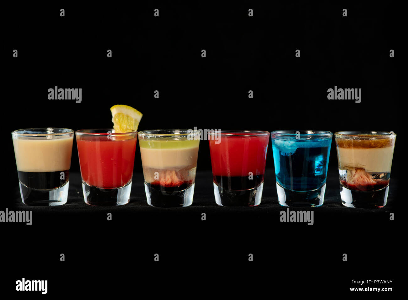 Various alcoholic cocktail shots together with isolated black ...