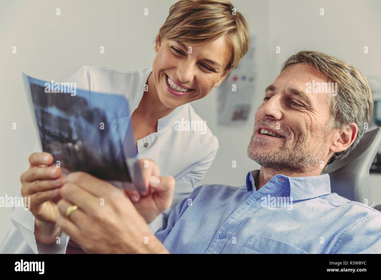 Dentist explaining x-ray image to smiling patient Stock Photo - Alamy