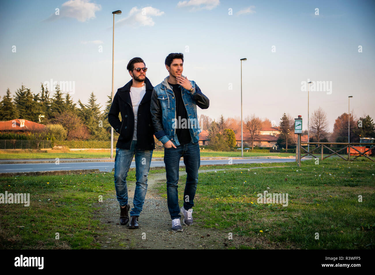 Two handsome casual trendy young men, 2 friends, in an urban park ...